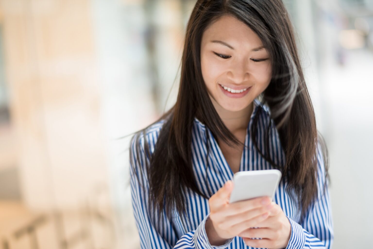 Asian business woman texting on her cell phone at the office and ...